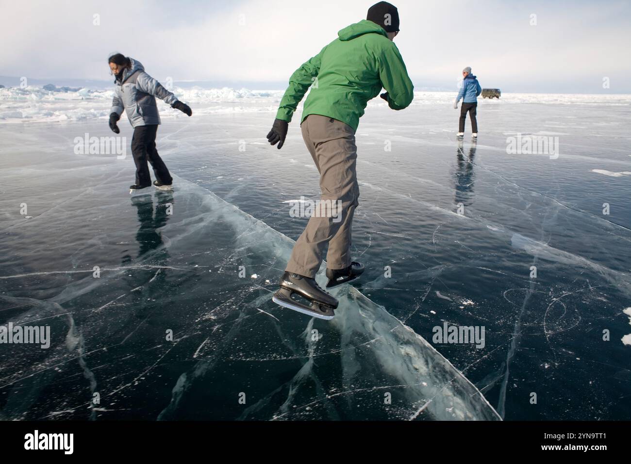 Three people ice skating on the frozen lake Baikal, Siberia, Russia ...