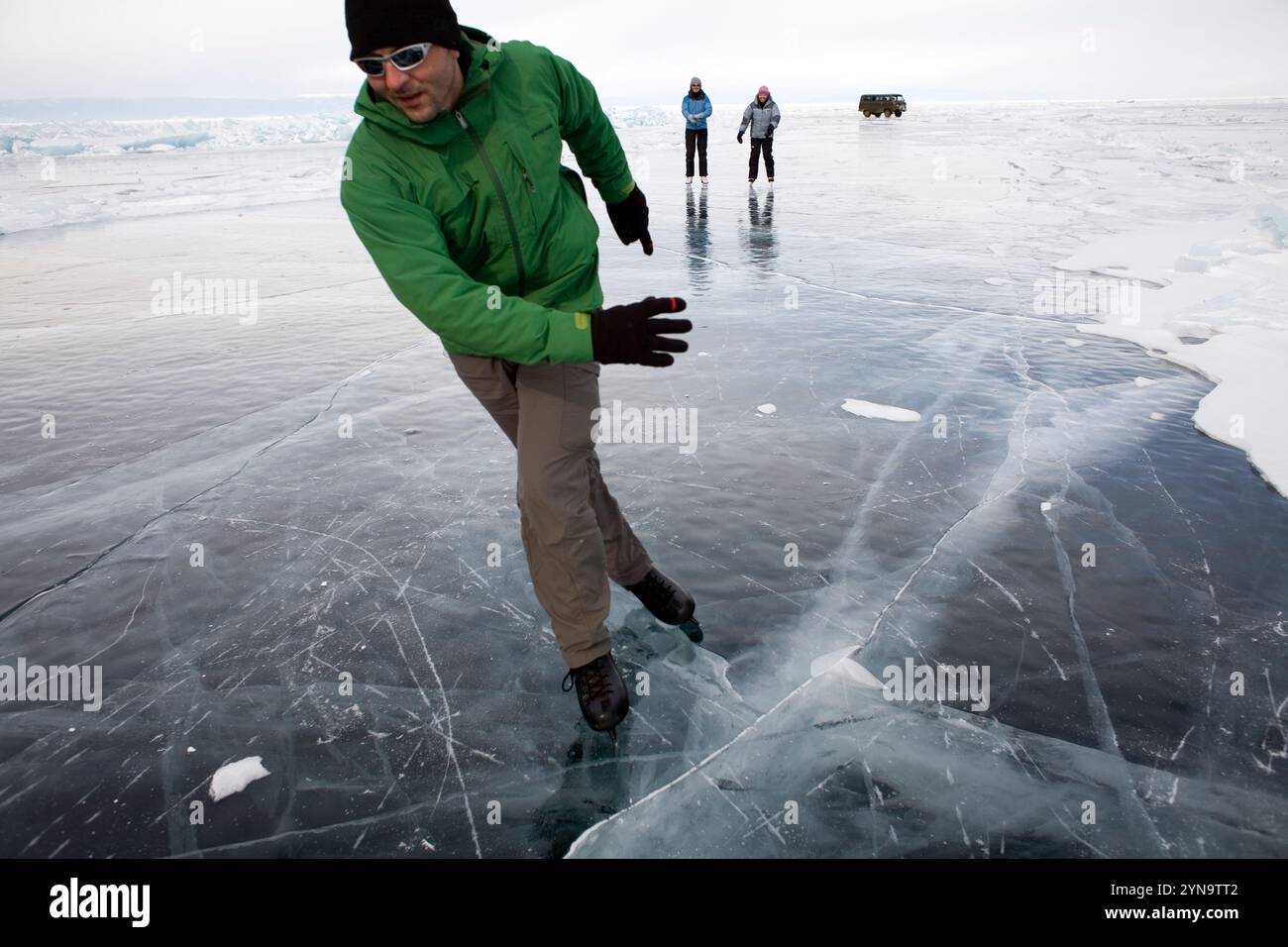 Three people ice skating on the frozen lake Baikal, Siberia, Russia ...