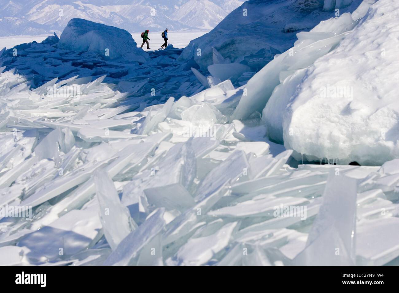 Two people hiking during winter on the frozen Lake Baikal in Siberia ...