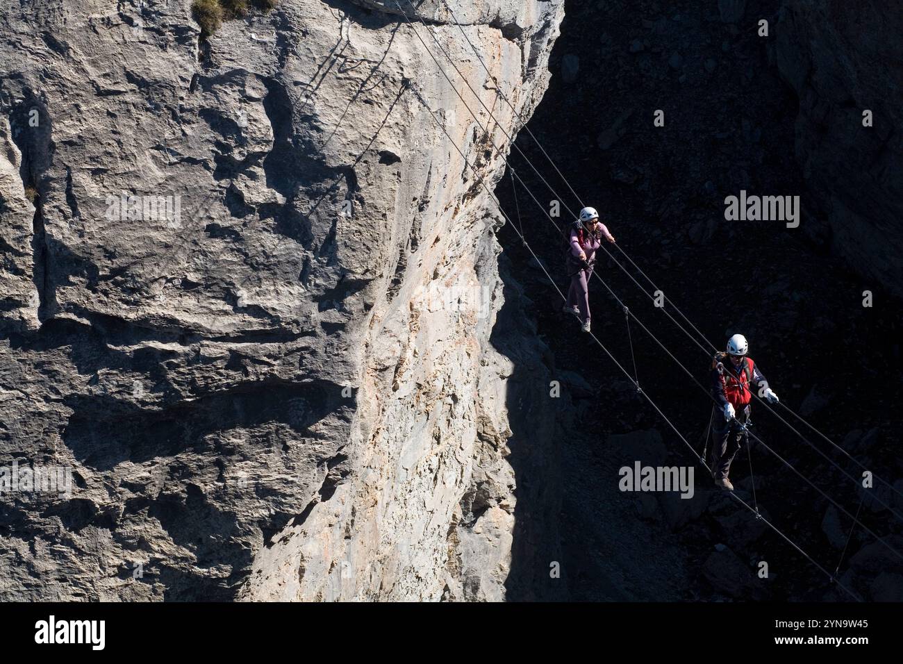 Two people walking across the tight cable bridge section of a Via ...