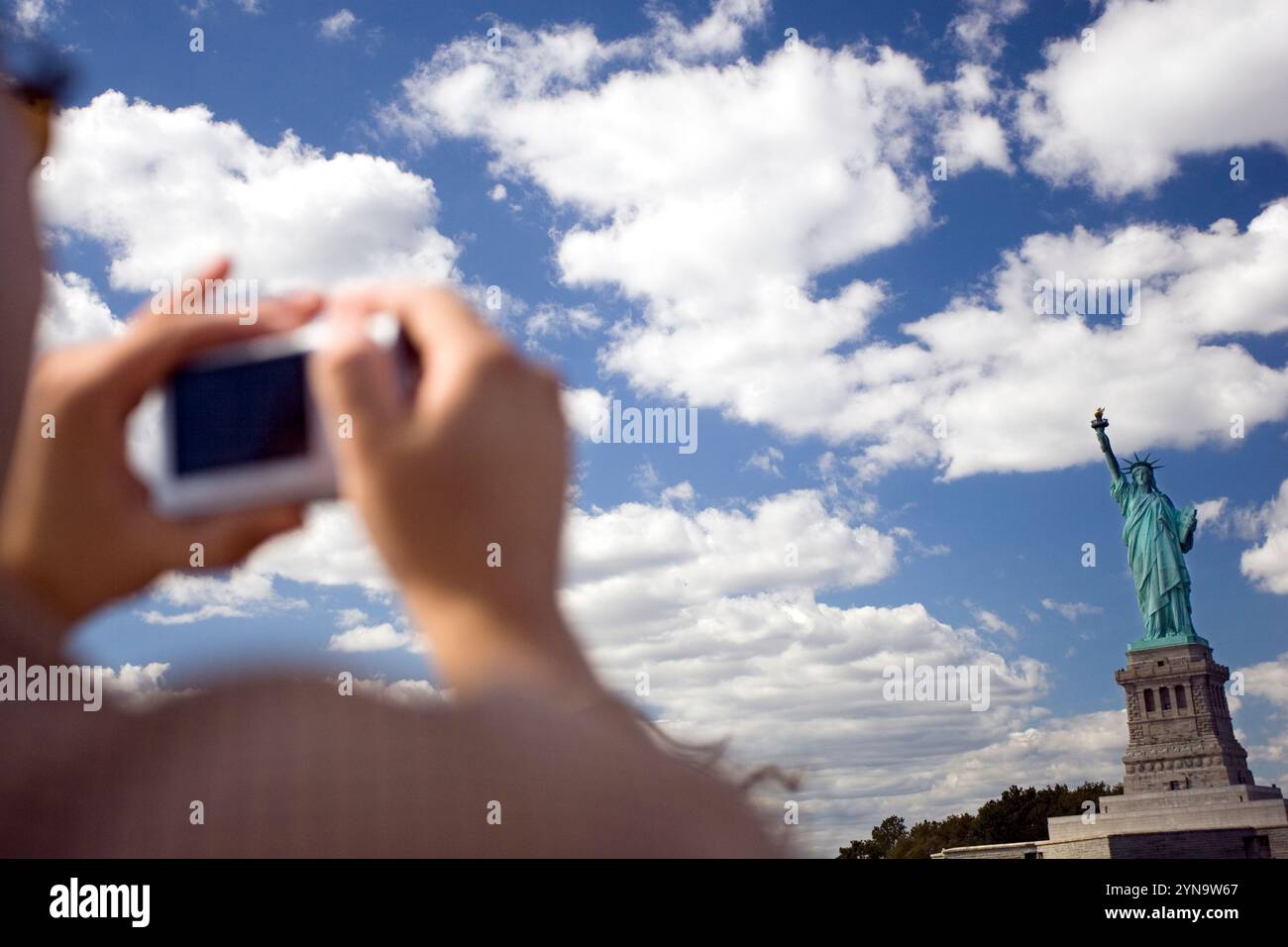 A tourist taking a photo of the Statue of Liberty from aboard a ferry in New York City, New York ...