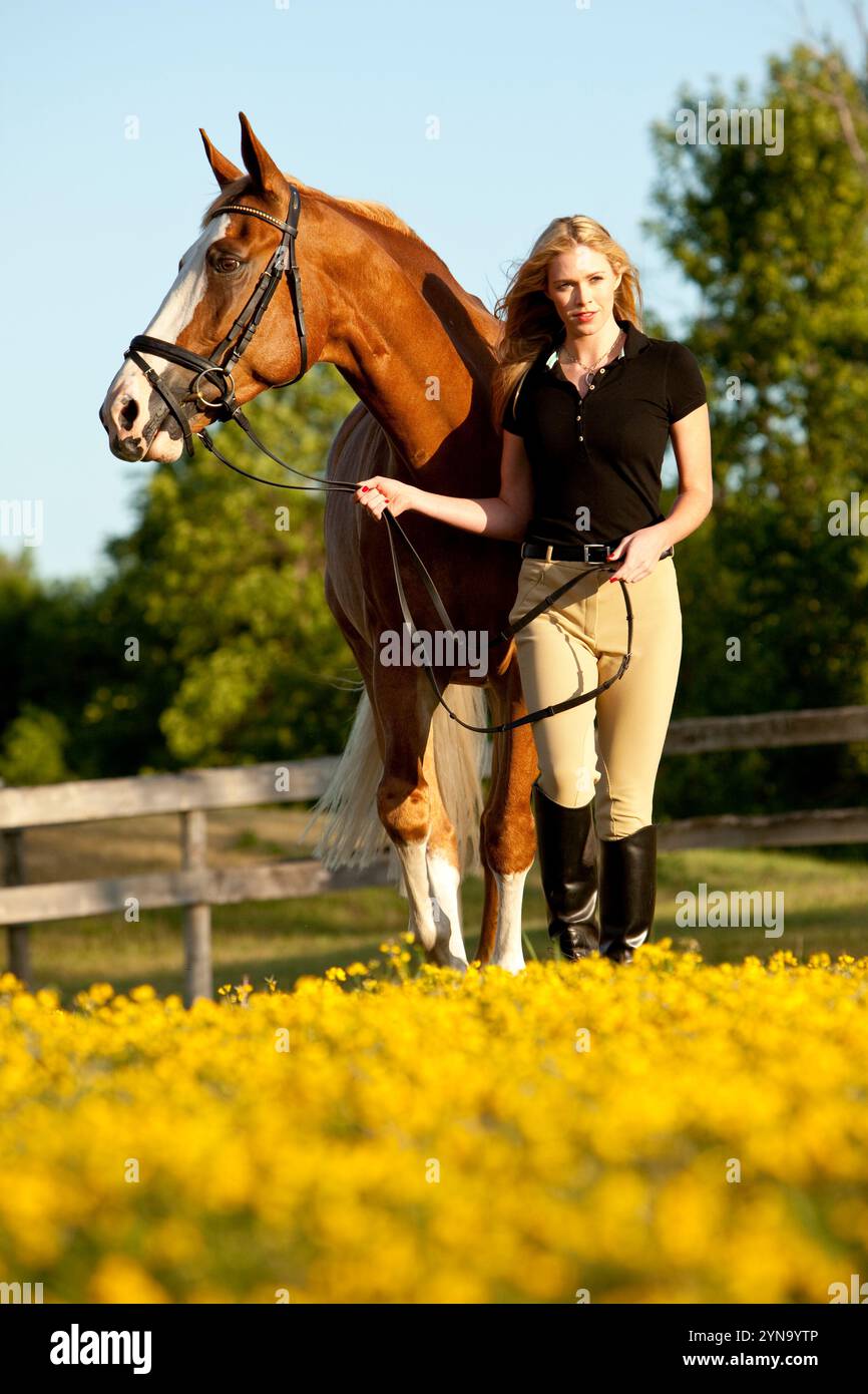 A woman walks a horse in a flowered stable during a lifestyle shoot at ...