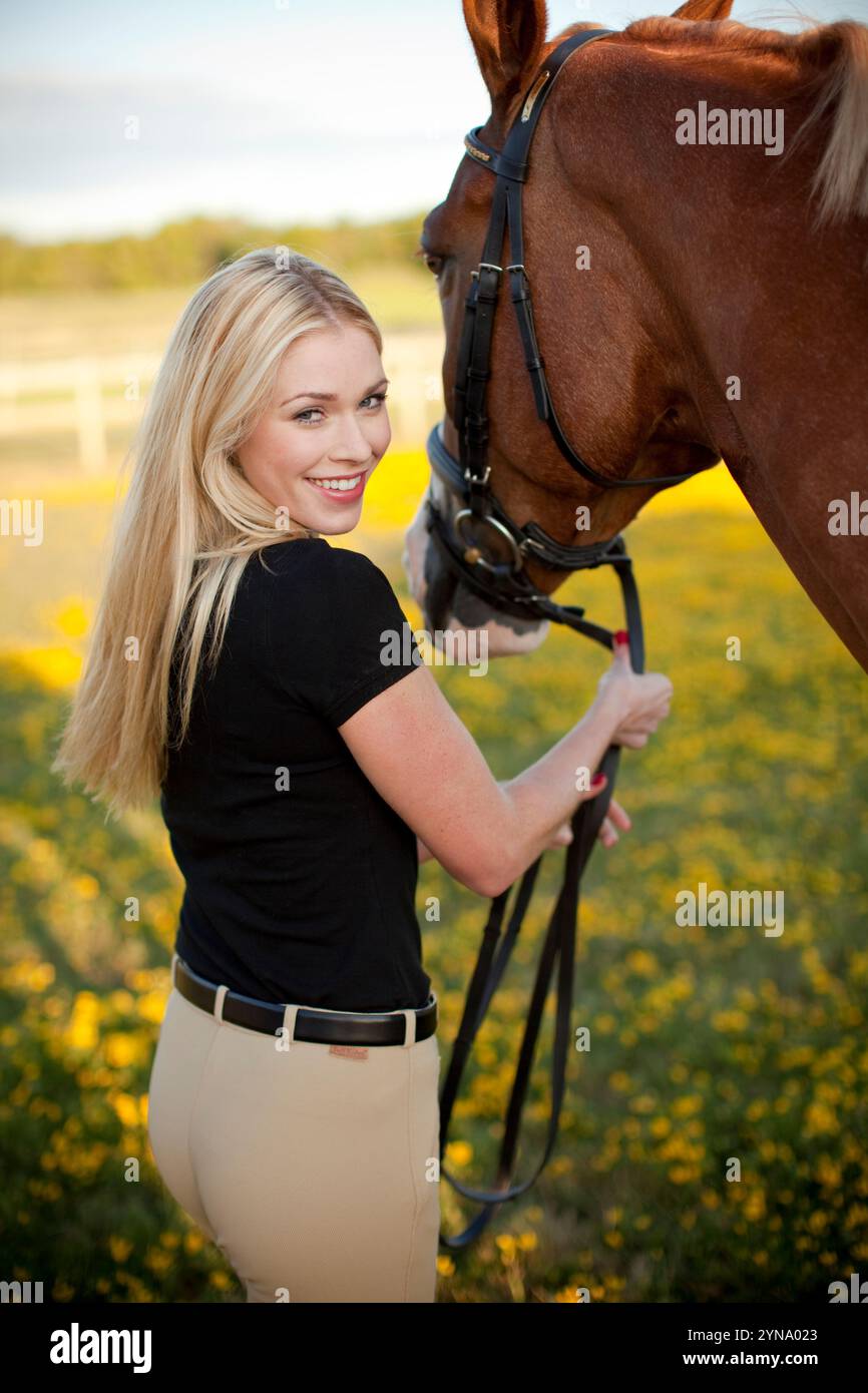 A woman poses with a horse in a flowered stable during a lifestyle ...