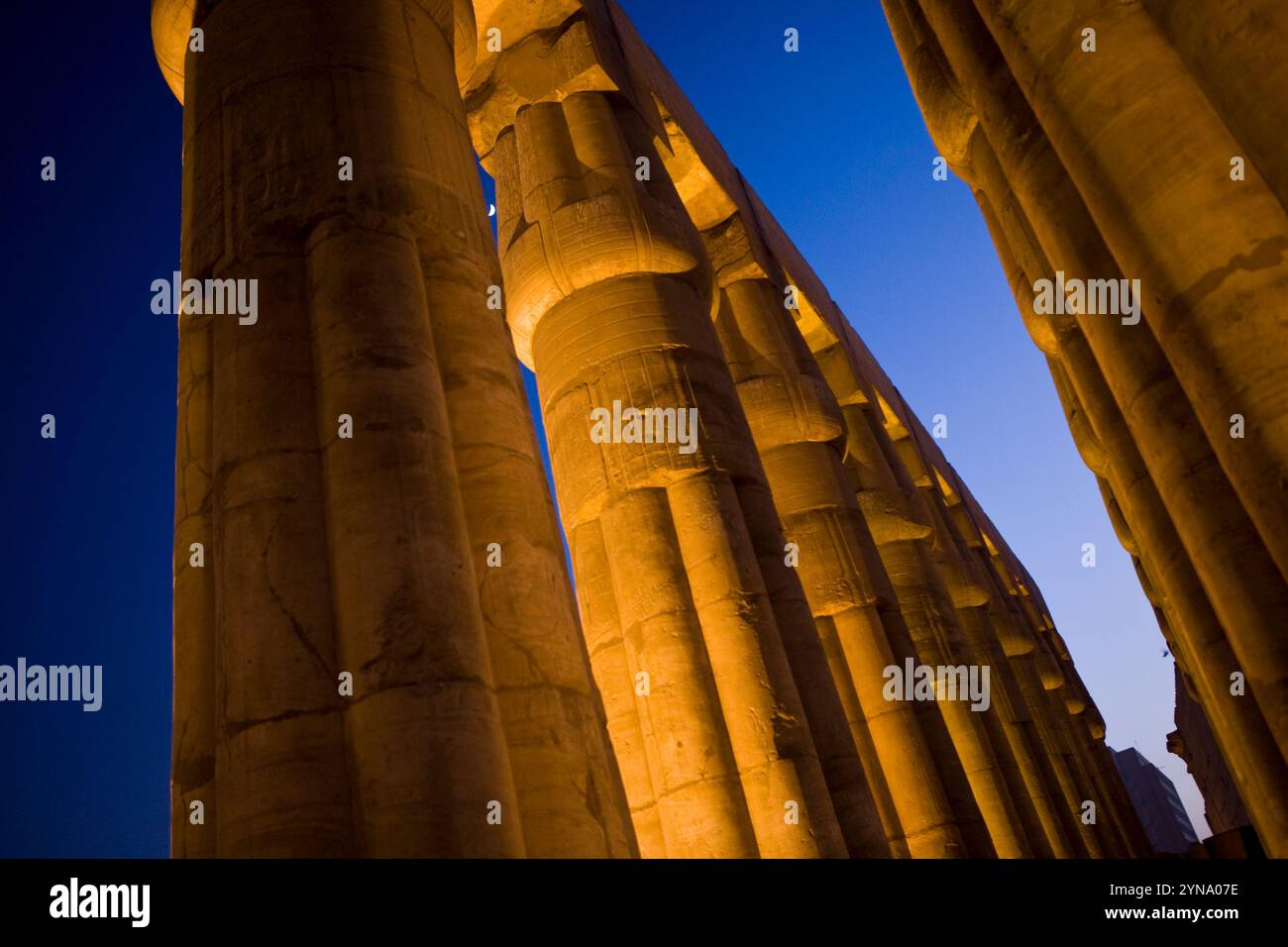 A crescent moon rises between the immense pillars of Luxor Temple ...