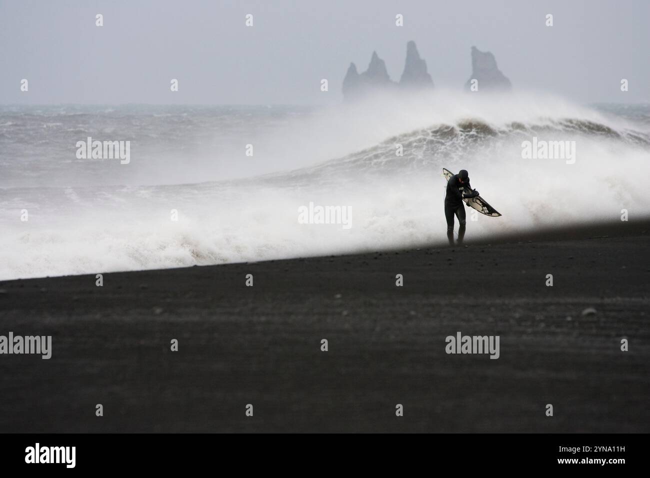 Winter surfer walks up windy beach Stock Photo - Alamy