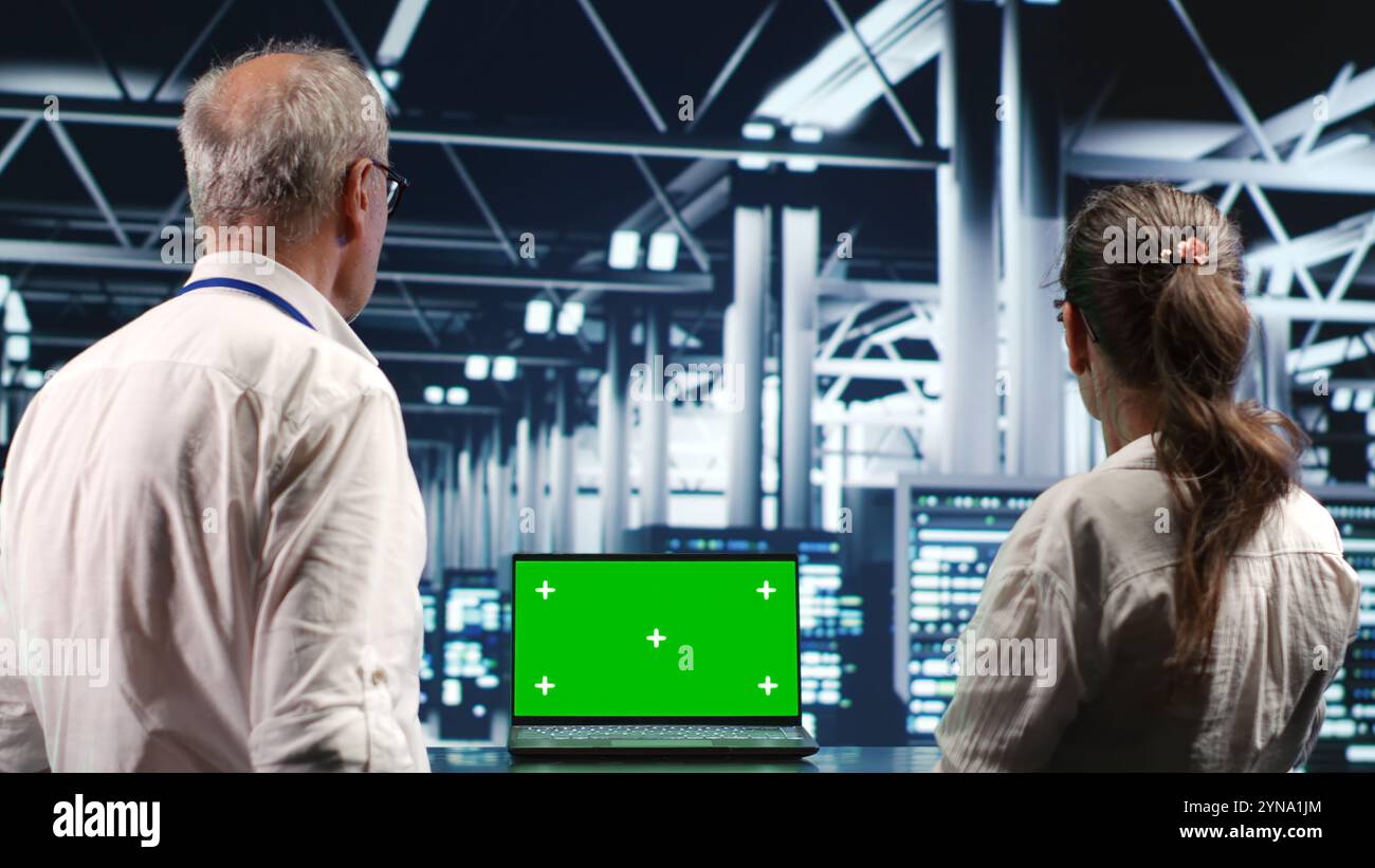 Licensed IT admins looking around high tech data center, using chroma key laptop to crosscheck ...