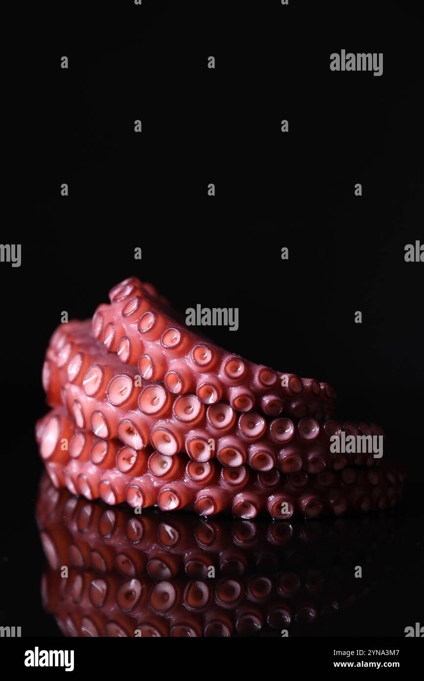 Cut fresh raw octopus on black mirror surface Stock Photo - Alamy