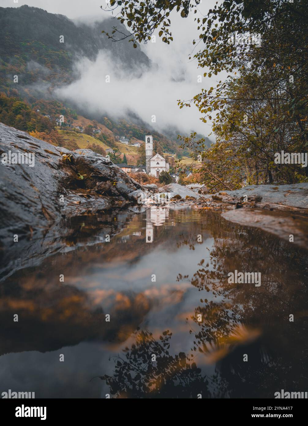 A rainy autumn landscape with vibrant foliage surrounds a gently ...