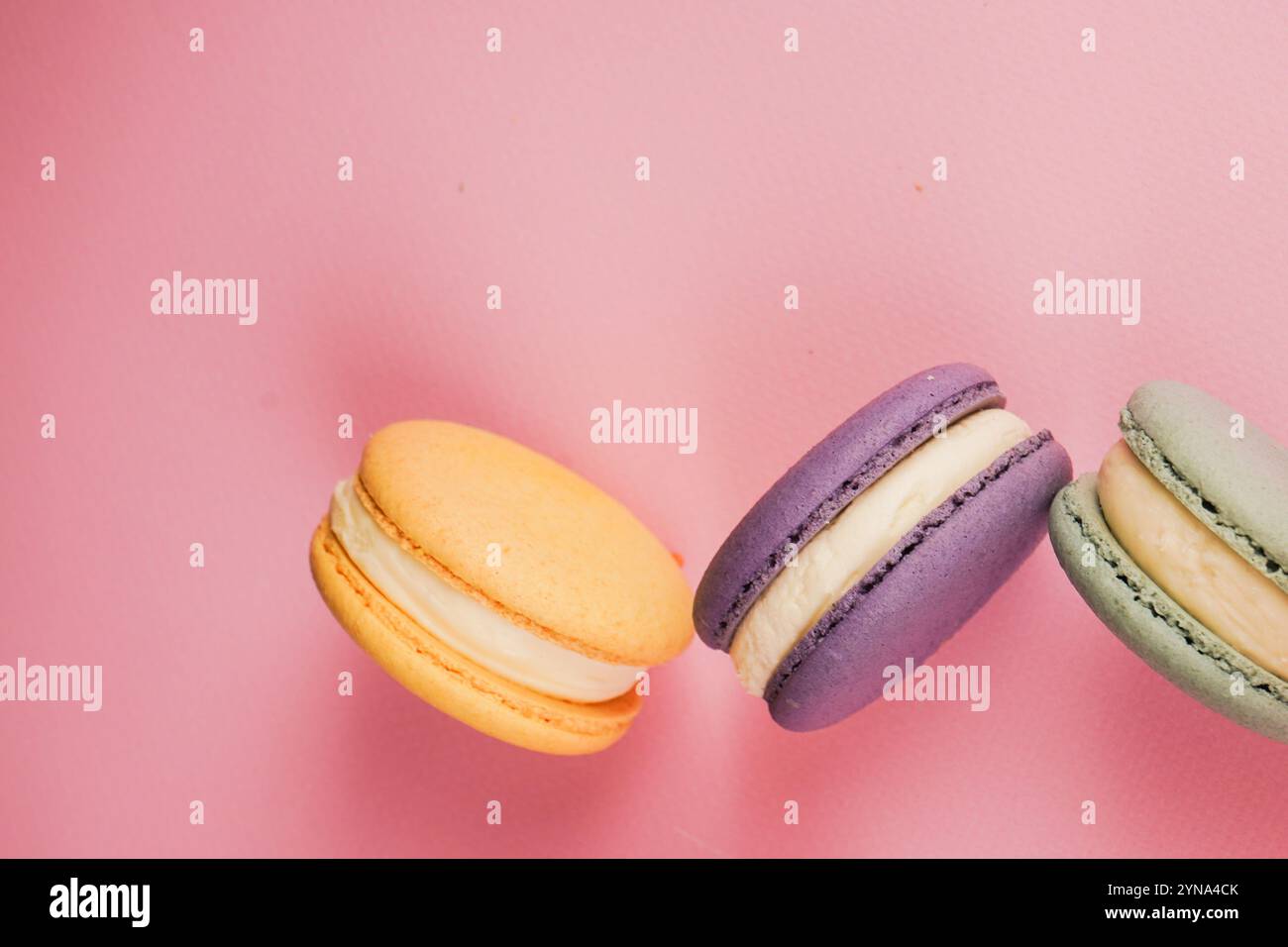 A row of brightly colored macarons on a pink base. Delicious French ...