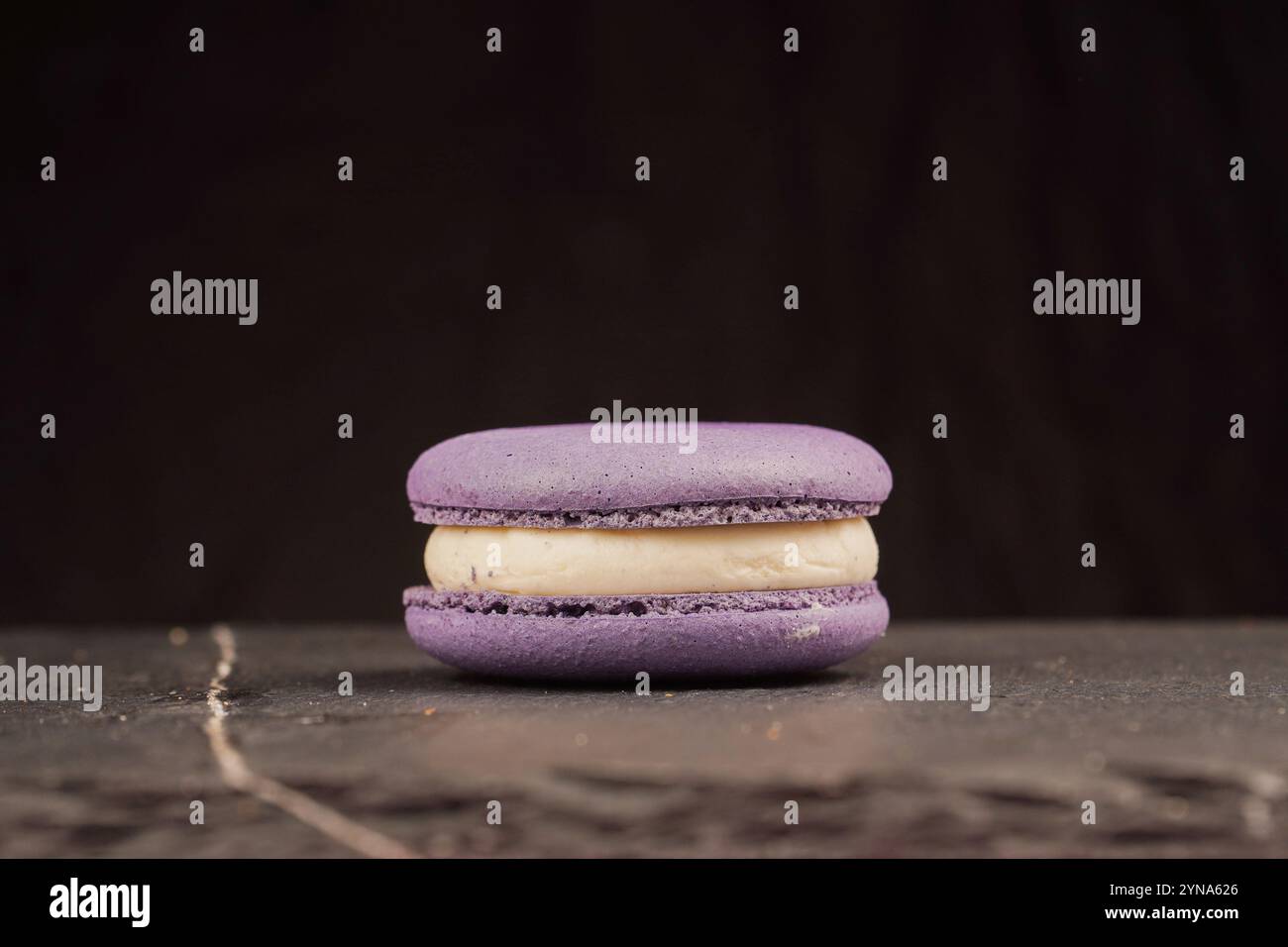 Premium macarons with a purple cream filling, presented on a black ...