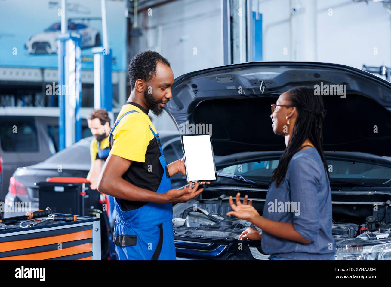Mechanic in car service uses mockup tablet to order new compressor belt ...