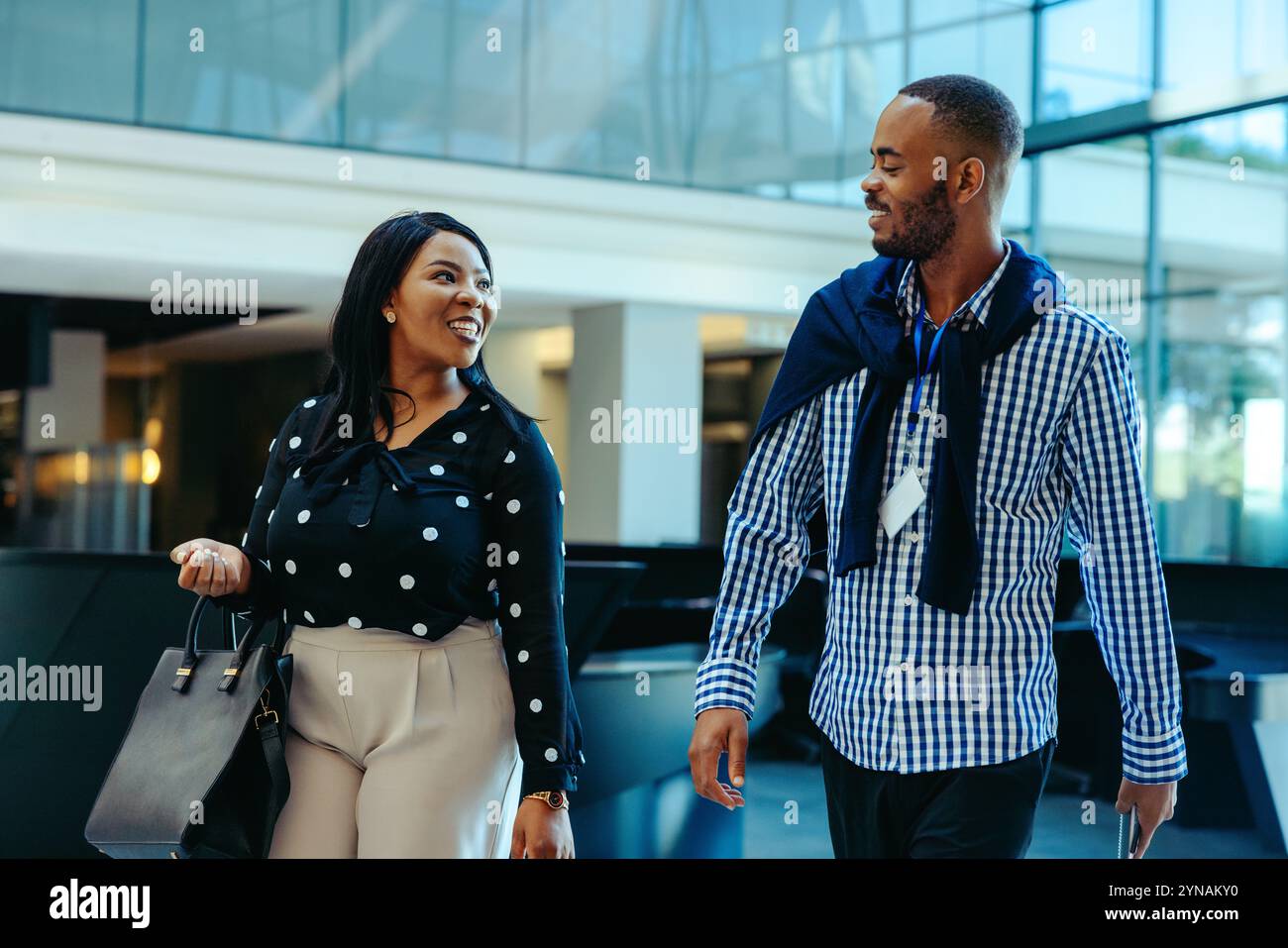Two professional colleagues walking in a modern office setting ...