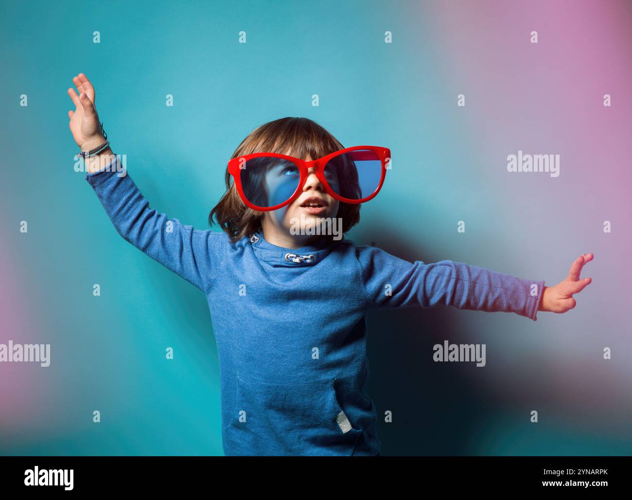 A young child wears large red sunglasses while striking a playful pose ...