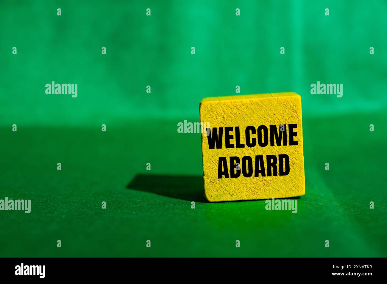 Welcome aboard message written on yellow wooden cube with green ...
