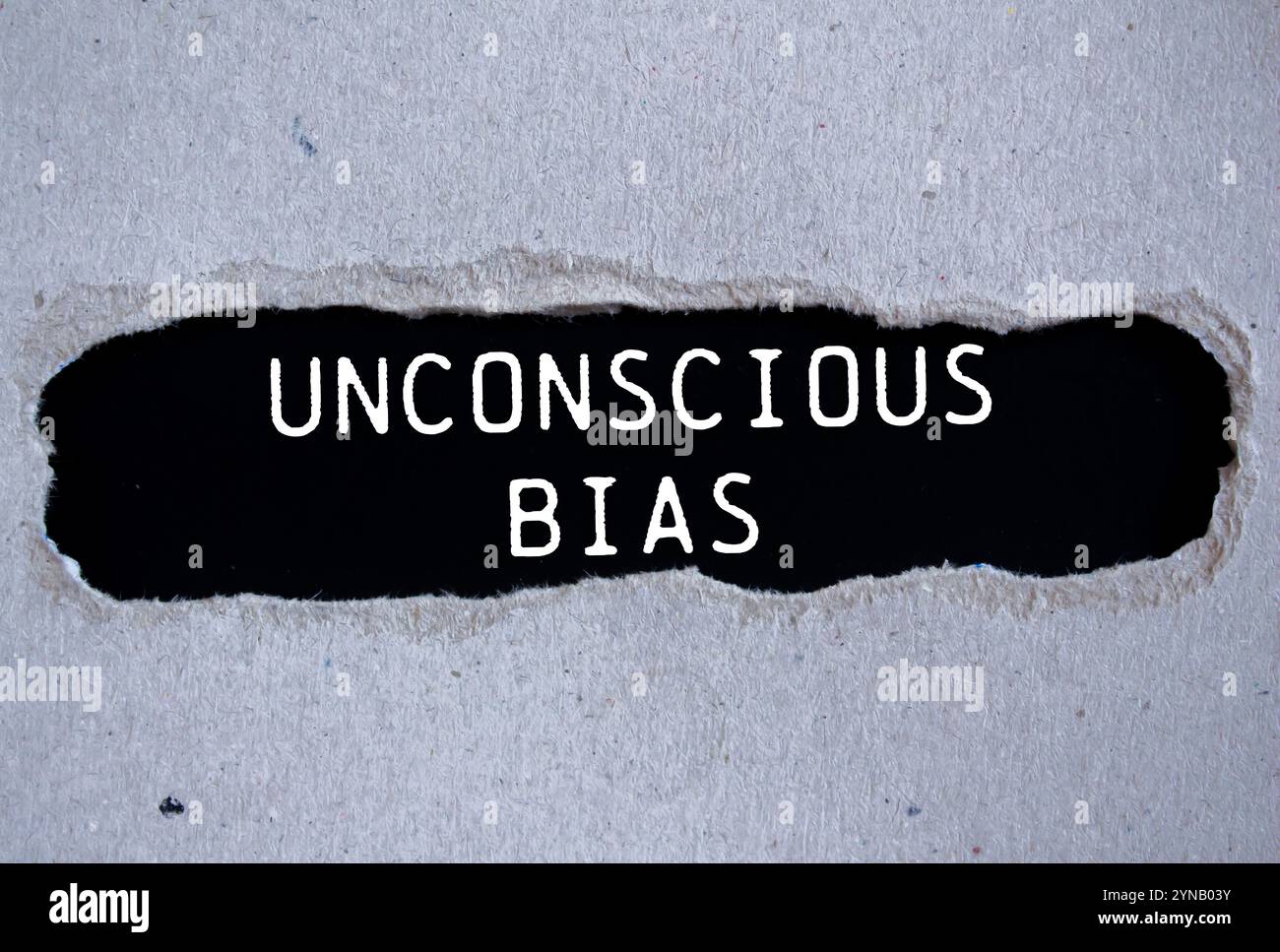 Unconscious bias message written on ripped torn gray paper with black background. Conceptual ...