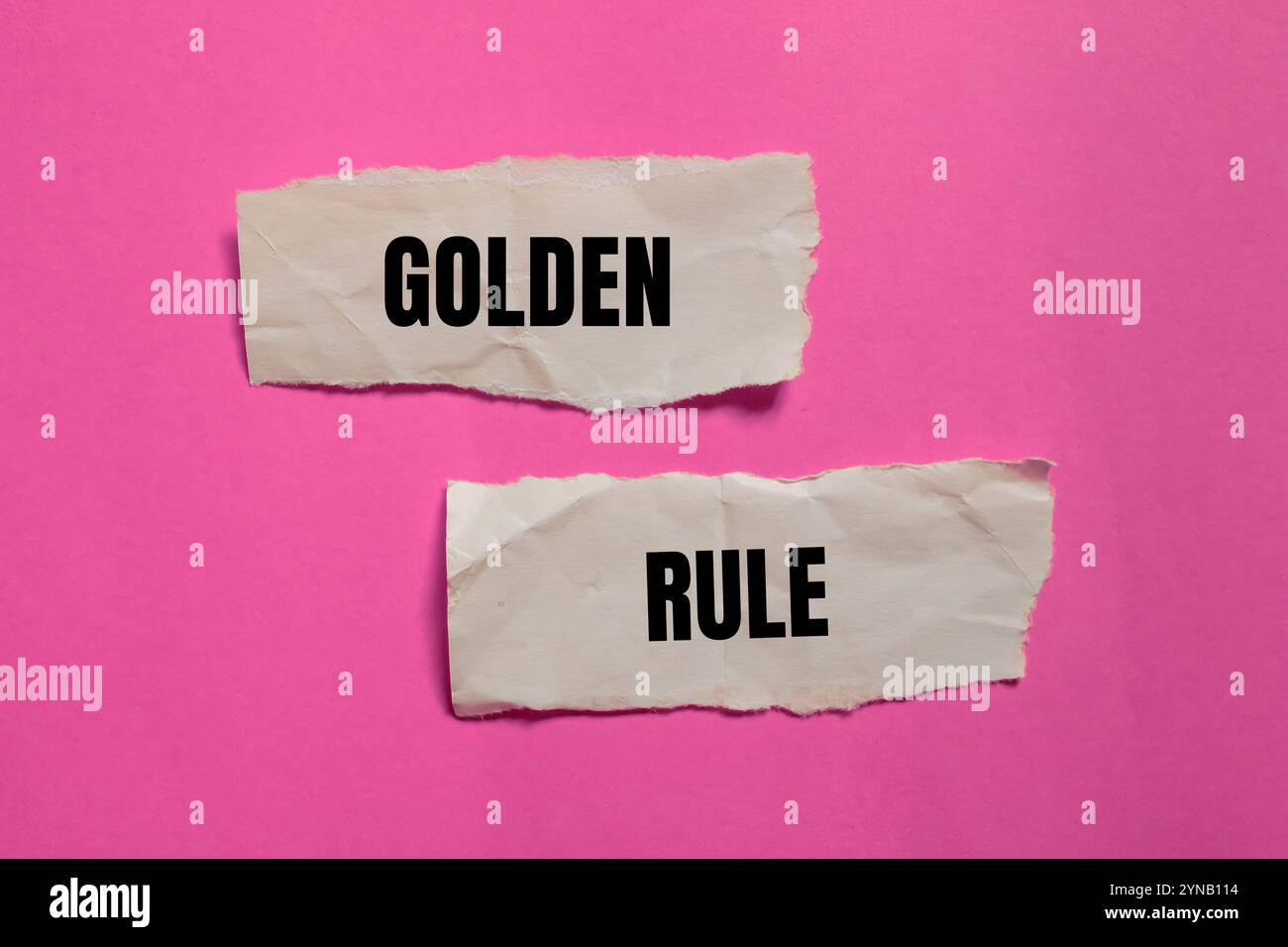 Golden rule message written on ripped paper pieces with pink background ...