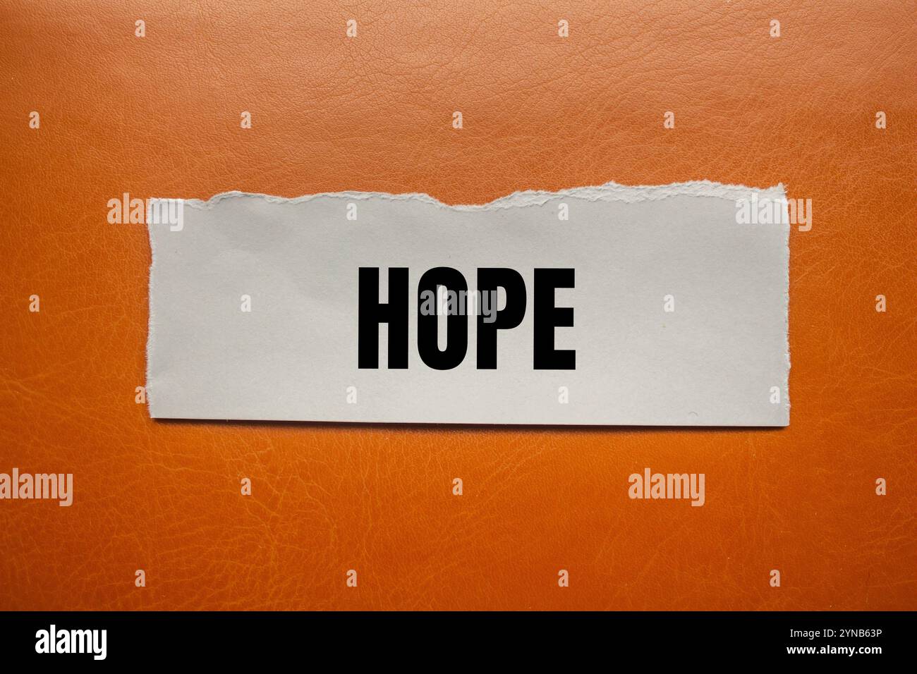 Hope message written on ripped torn paper piece with brown background. Conceptual hope symbol ...