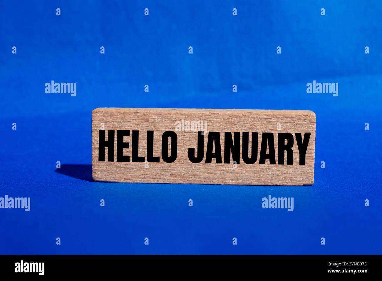 Hello january message written on wooden block with blue background ...