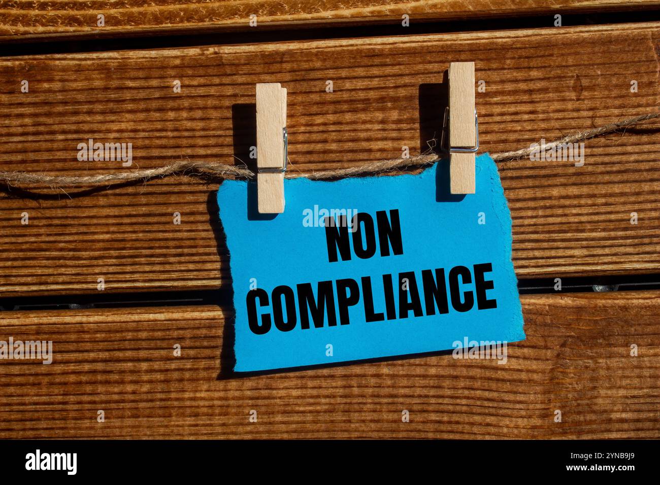 Non compliance message written on ripped blue torn paper piece with ...