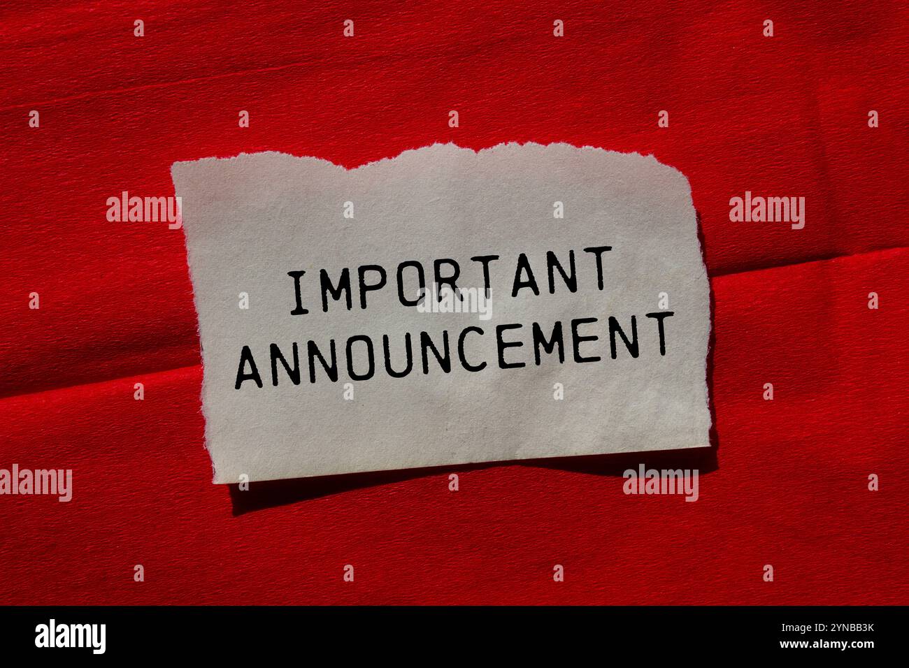Important announcement message written on ripped torn paper piece on red background. Conceptual ...