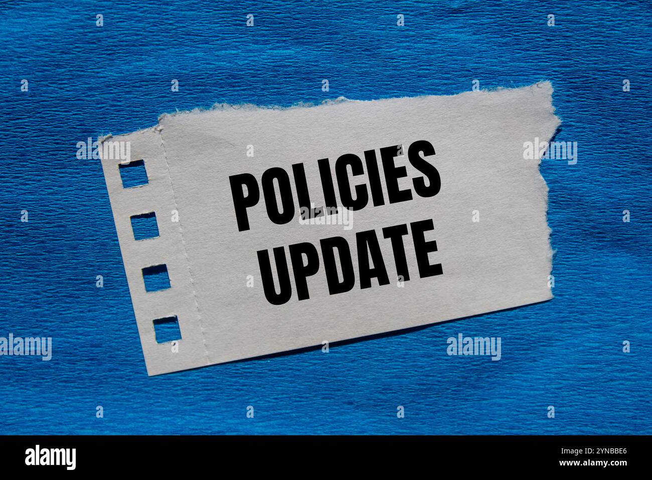 Policies update message written on ripped torn paper piece with blue background. Conceptual ...
