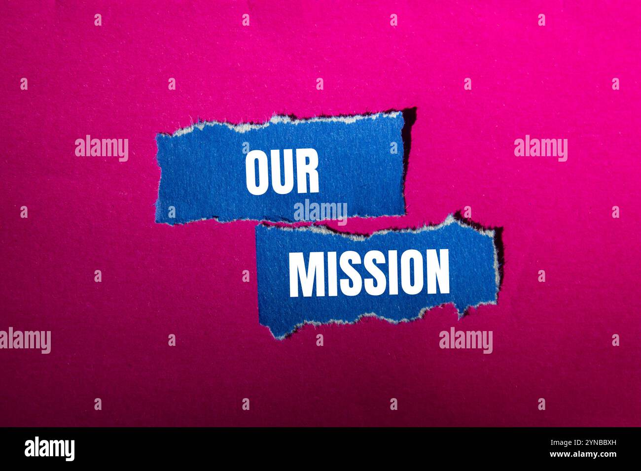 Our mission message written on ripped torn blue paper pieces with pink background. Conceptual ...