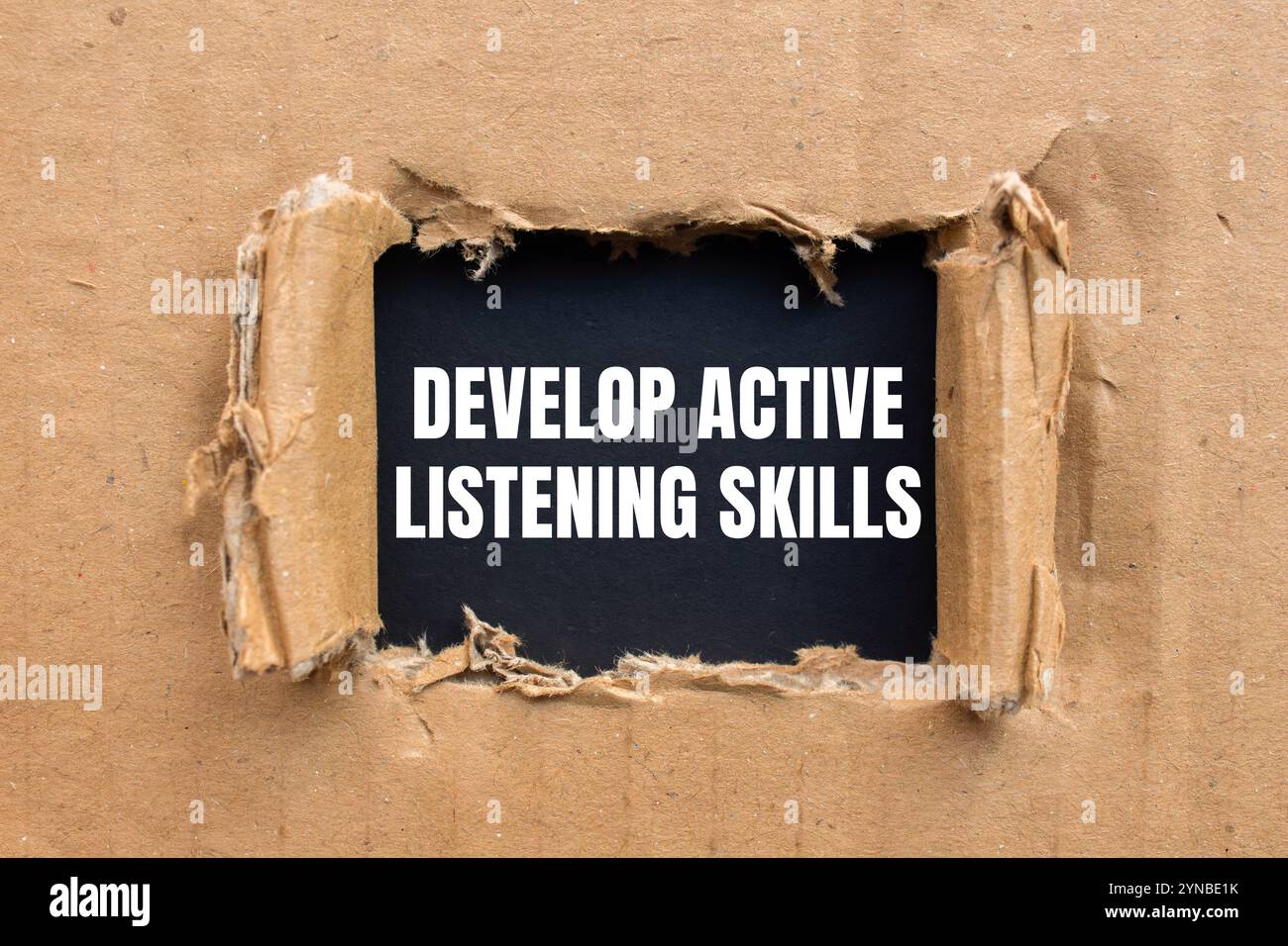 Develop active listening skills message written on ripped torn cardboard paper with black ...