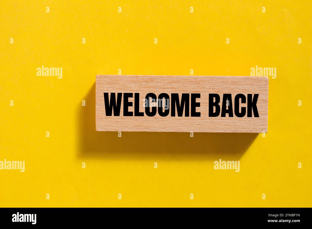 Welcome back message written on wooden block with yellow background ...