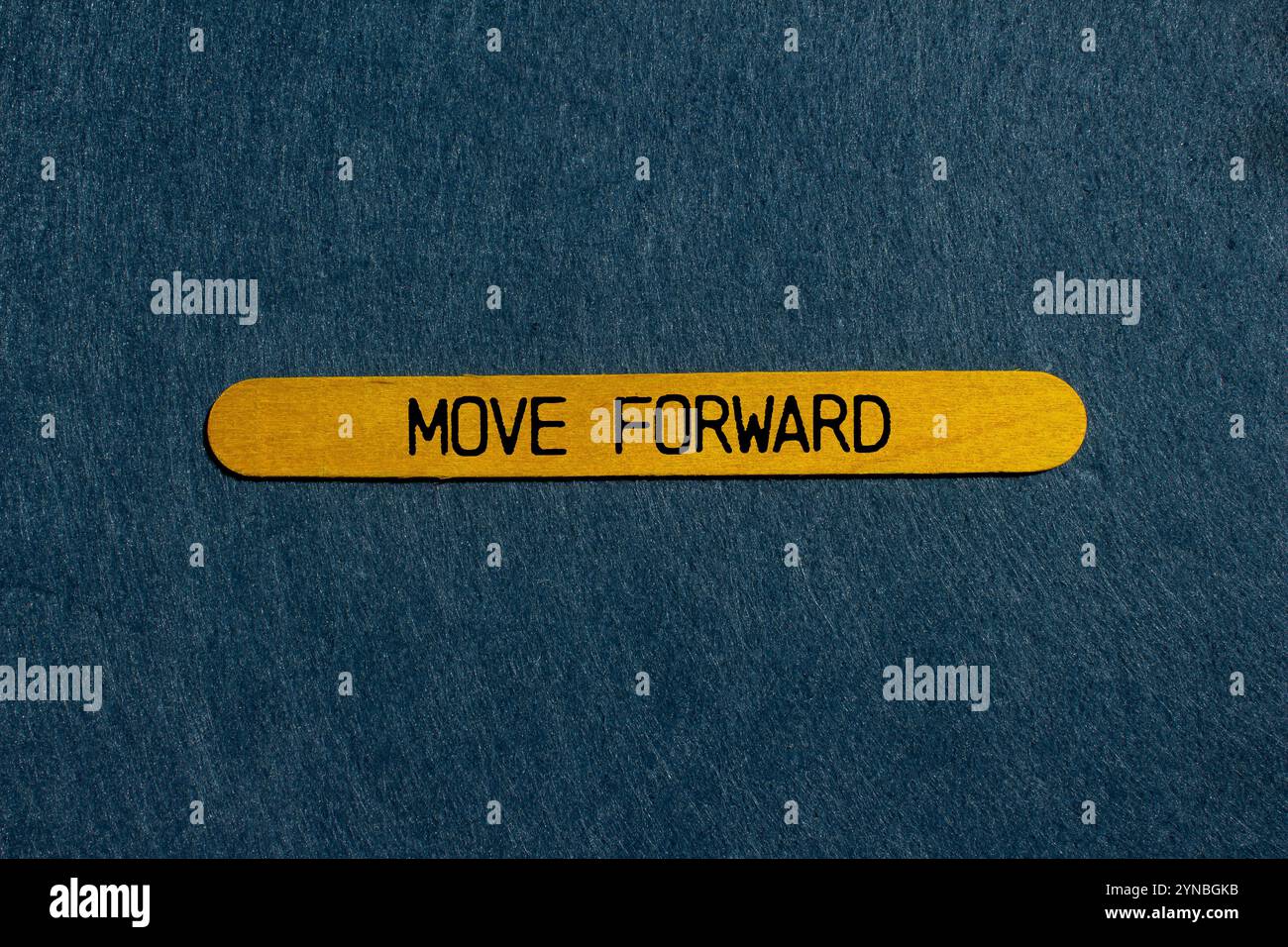 Move forward message written on yellow wooden stick with gray background. Conceptual move ...
