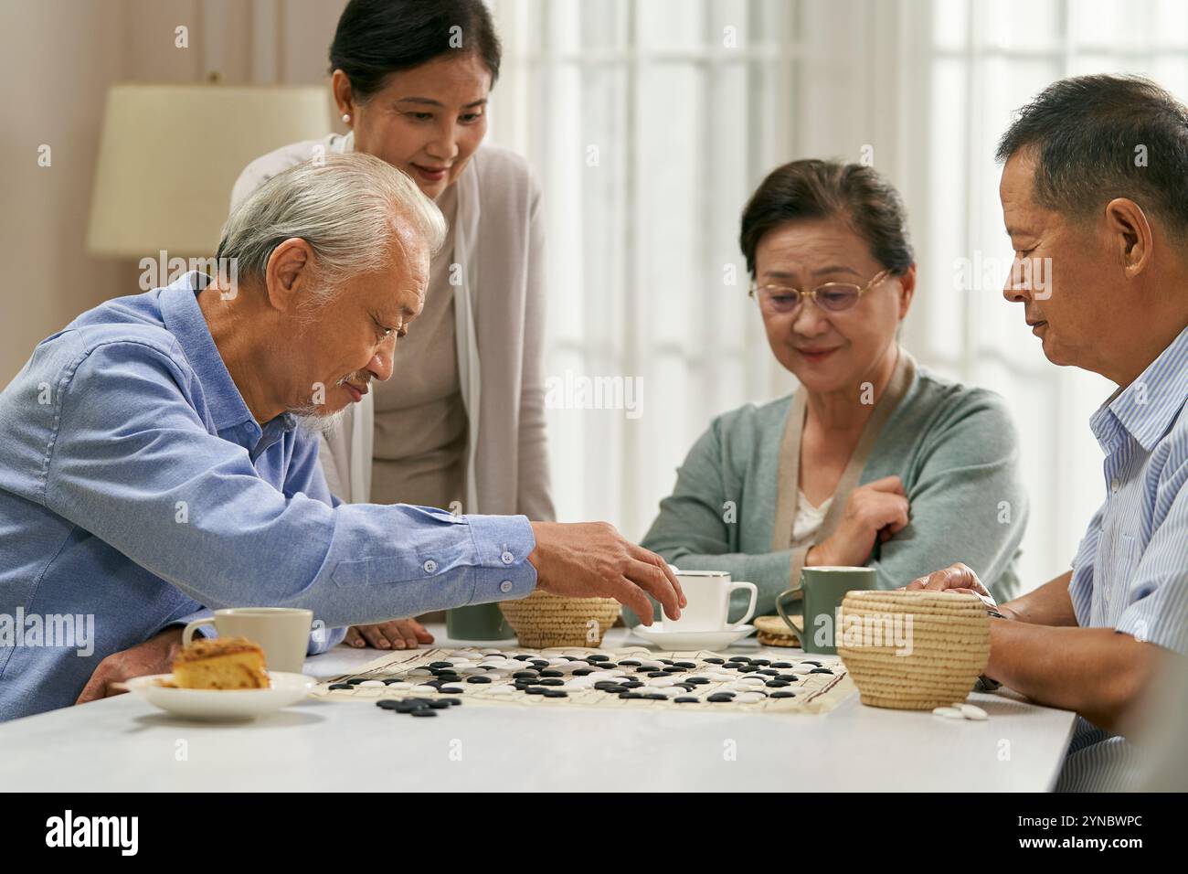 group of happy asian senior people gathering at home playing chinese ...