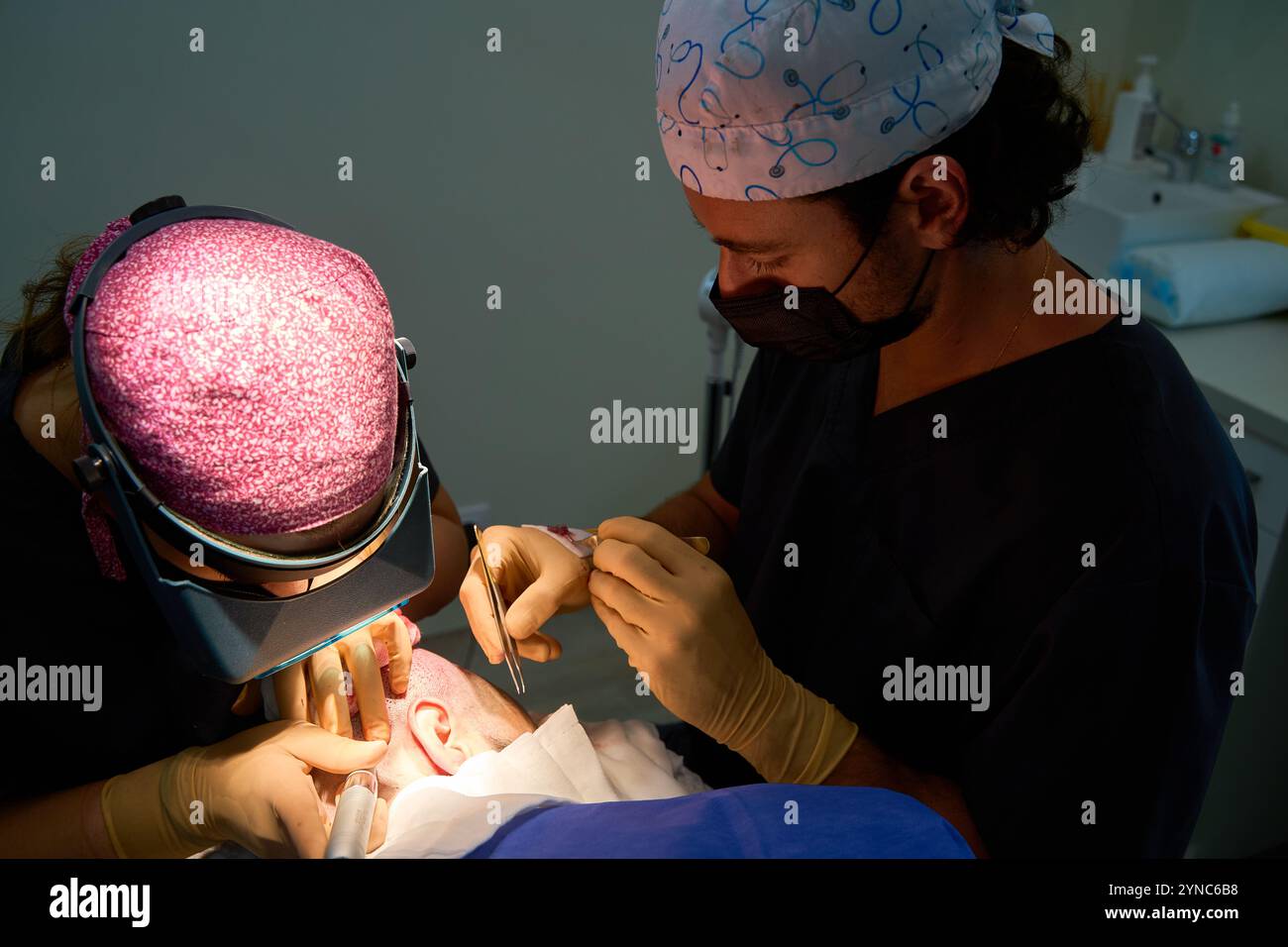 A team of surgeons conducting a hair transplant procedure with ...