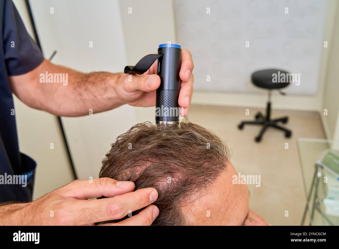 Doctor performing a hair and scalp examination using a diagnostic tool ...