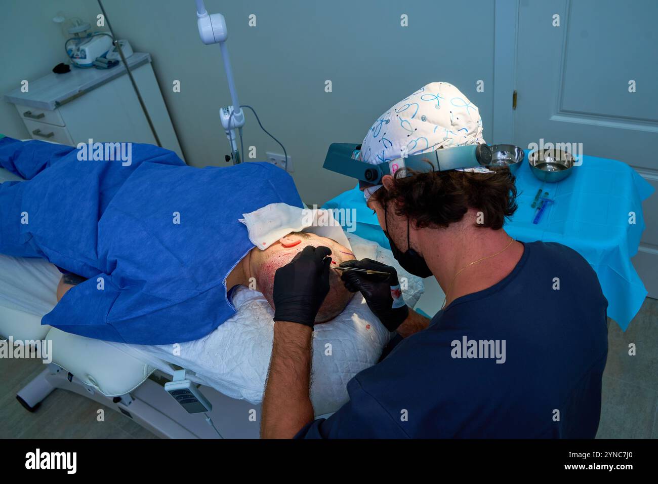 Surgeon performing hair transplant surgery on patient in operating room ...