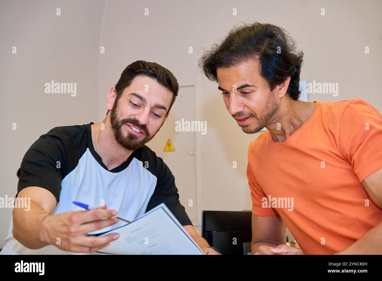 A man explains the clinic's rates to a client, showing a document with ...