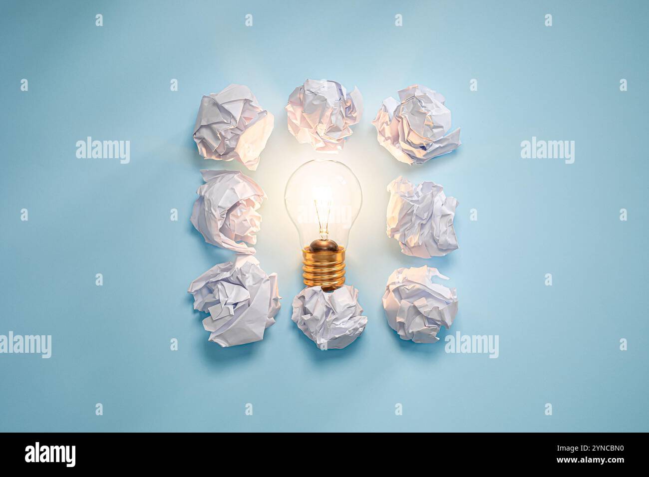 Creative ideas emerge from crumpled paper surrounding a glowing light ...