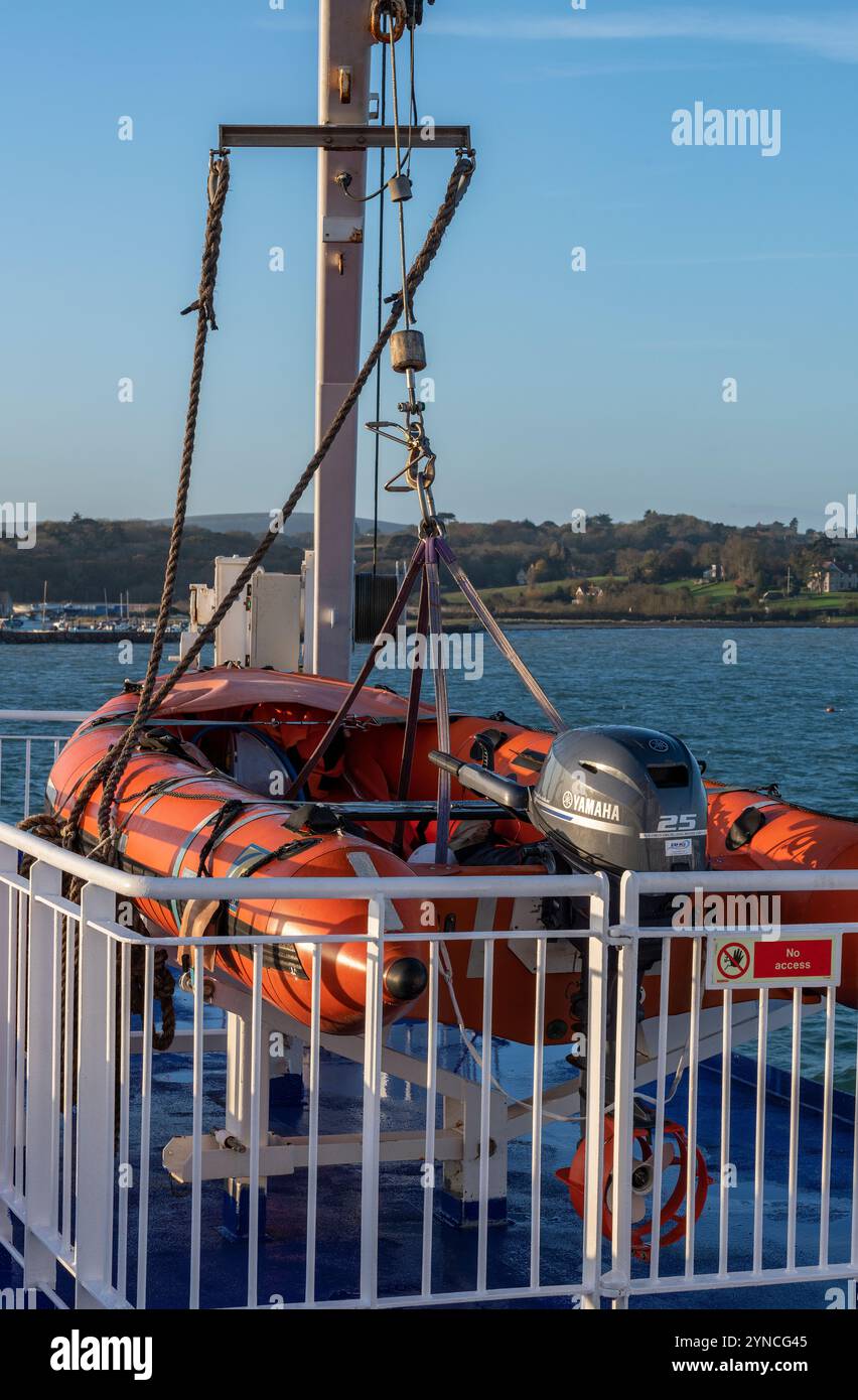 rescue dinghy or inflatable boat hanging from a davit hoist with an outboard engine for use in ...