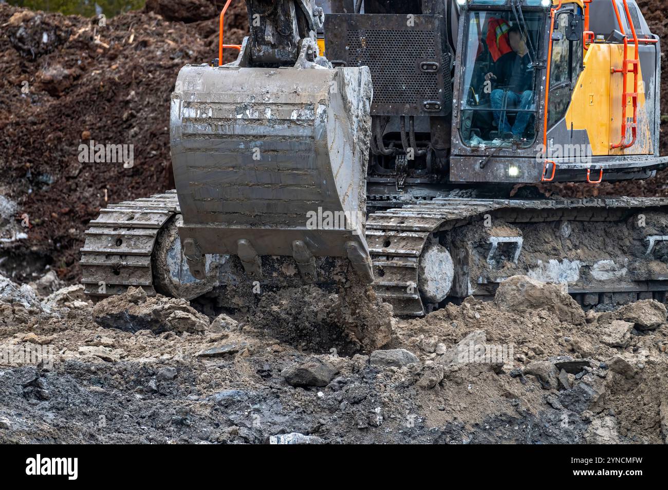Excavator bucket in close-up view, dumping soil Stock Photo - Alamy