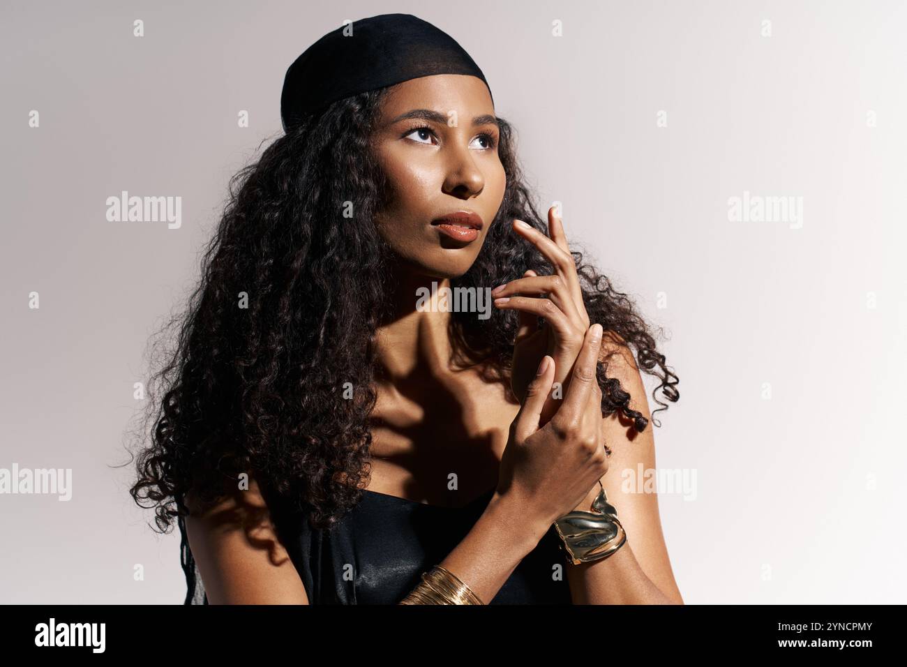 A striking woman with curly hair exudes elegance and poise, showcasing ...