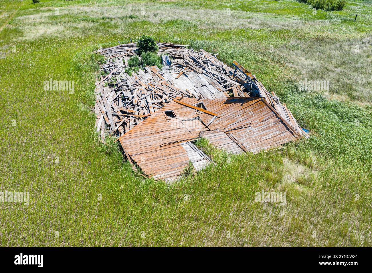 A large, dilapidated building sits in a field of grass. The building is ...