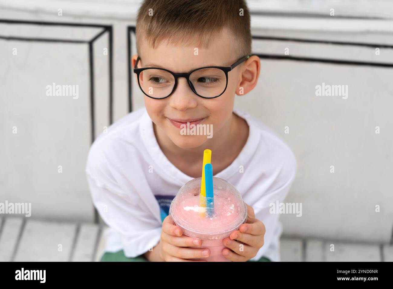 The boy smiles and holds a strawberry milkshake in his hands Stock ...