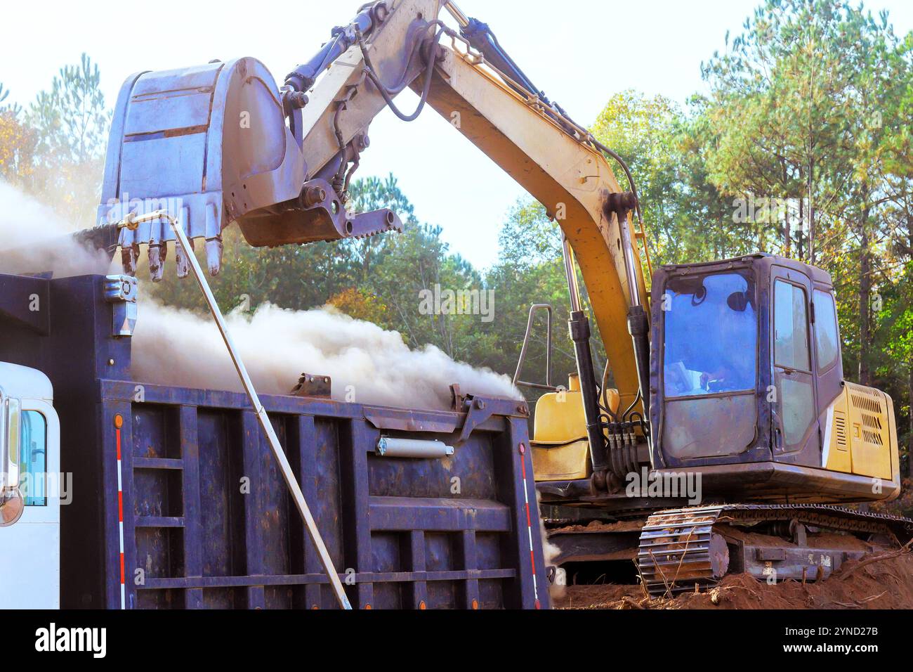 Under land removal, an excavator transfers large quantities of dirt ...