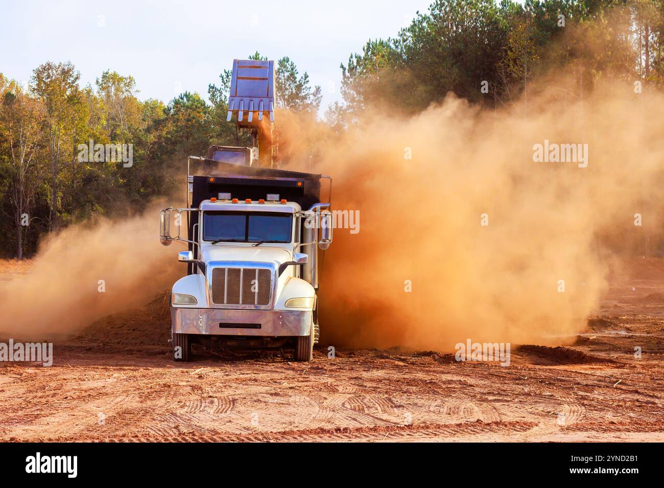 Construction truck is unloading materials at job site, sending cloud of ...
