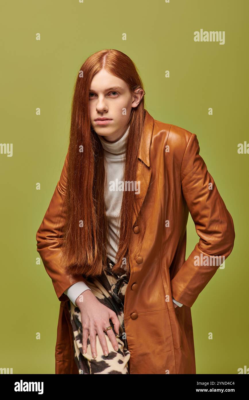 A young man with long red hair wears a striking outfit, conveying deep ...