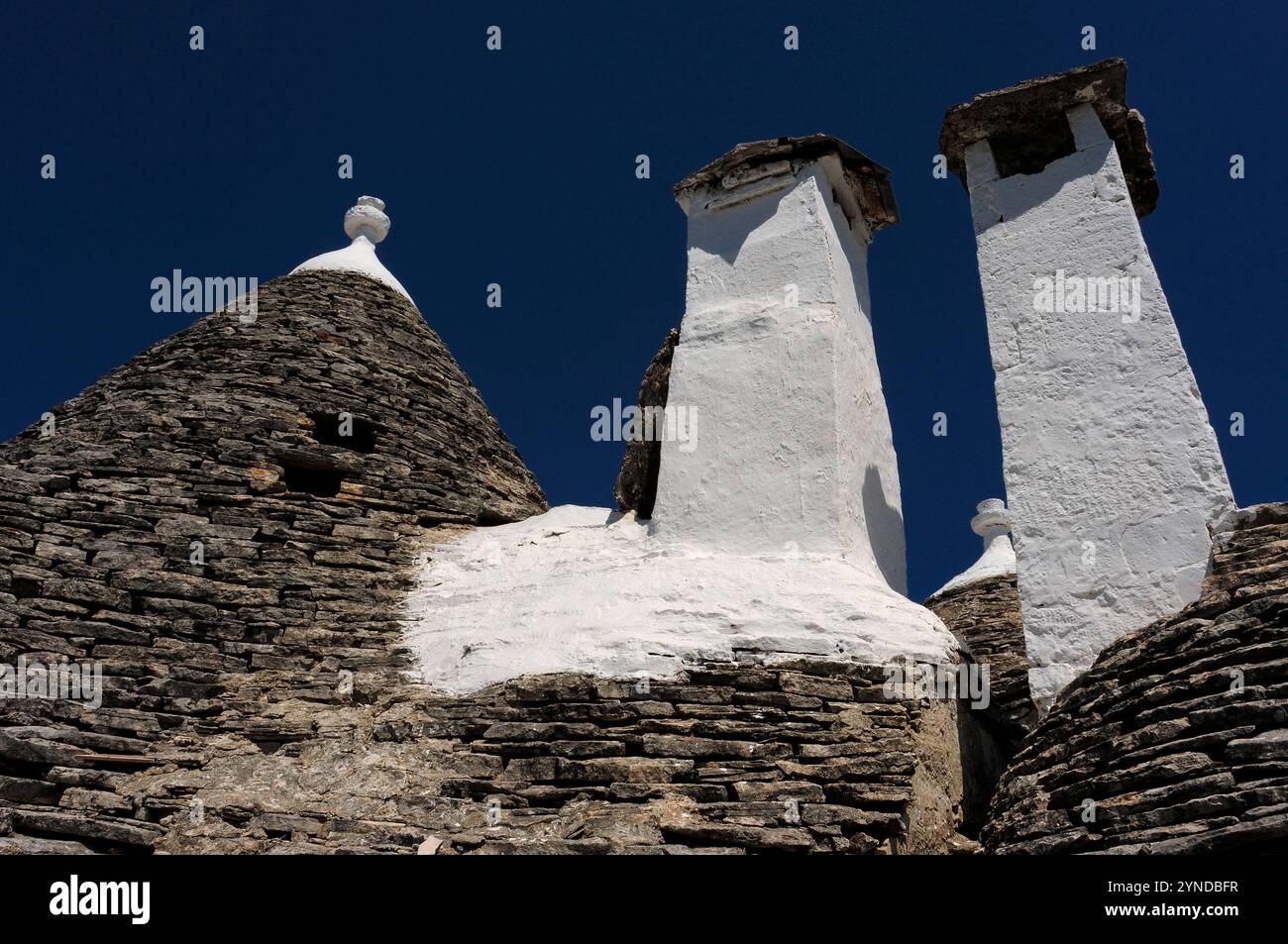 Tall chimneys and cones on neighbouring restored trulli in Alberobello ...