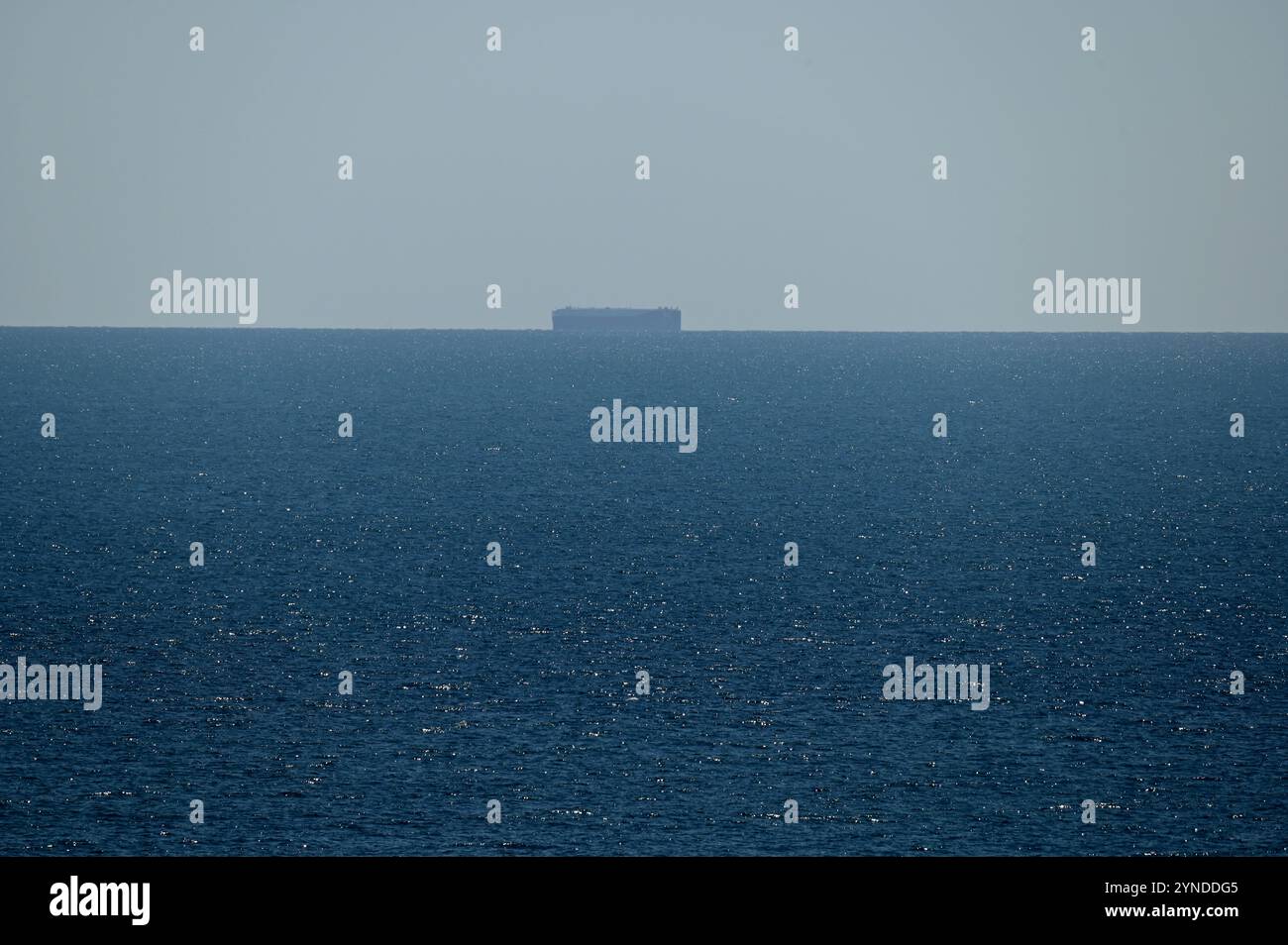 A large container ship in the distance, on the horizon, in an otherwise ...