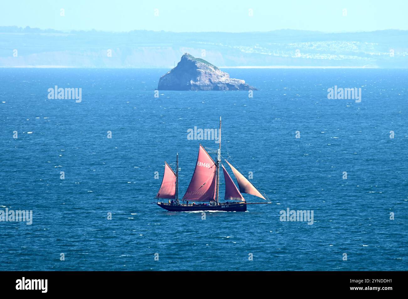 A traditional Brixham sailing trawler sets off on a calm morning in ...