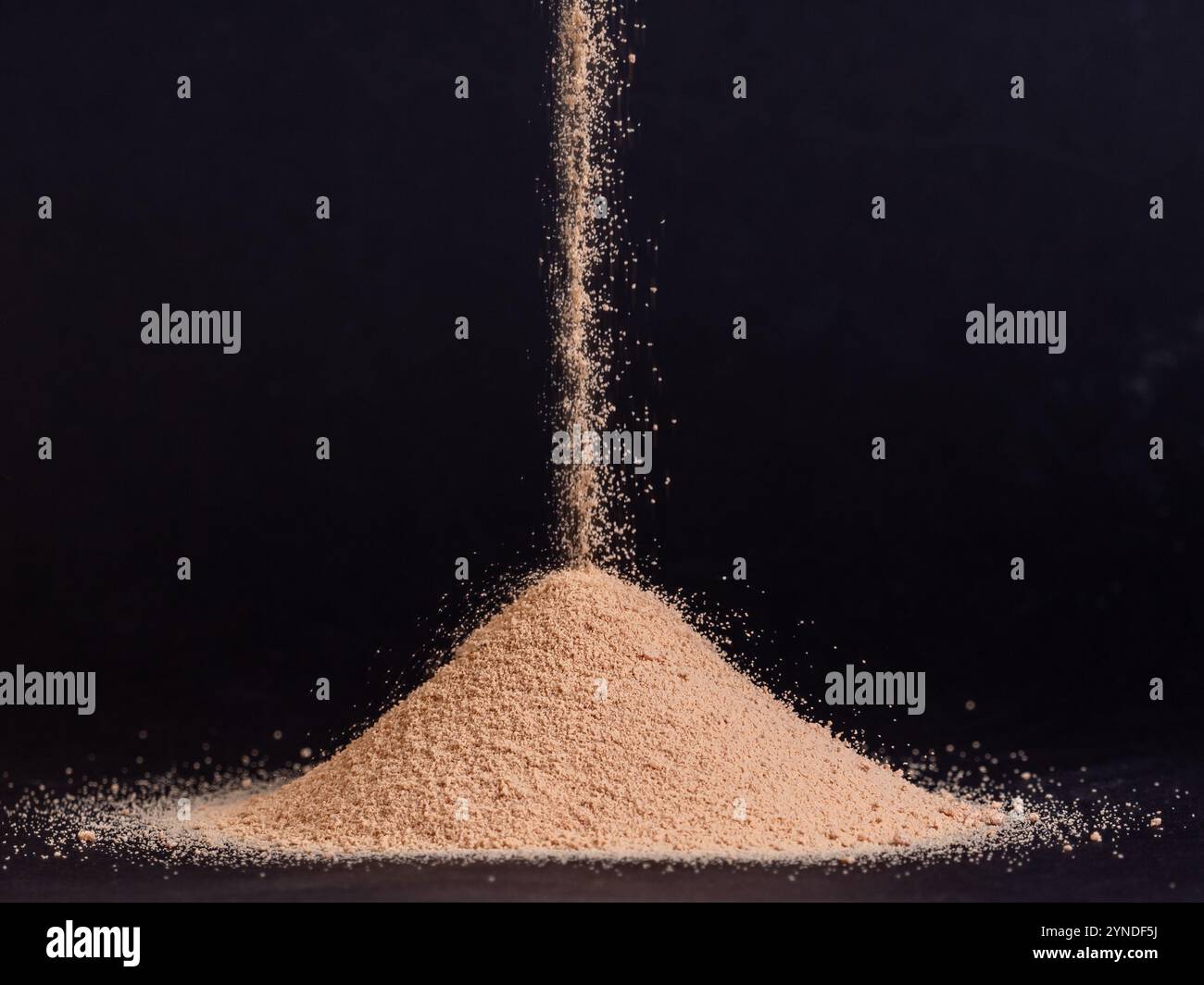 powder grains fall on a pile of powder on a dark background Stock Photo ...