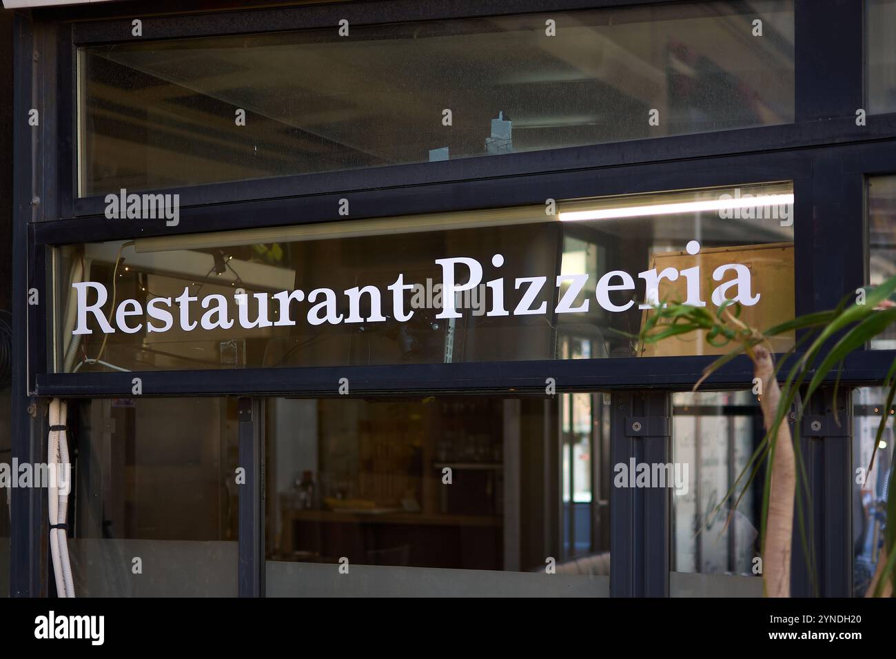 A modern restaurant pizzeria sign displayed on a glass window ...