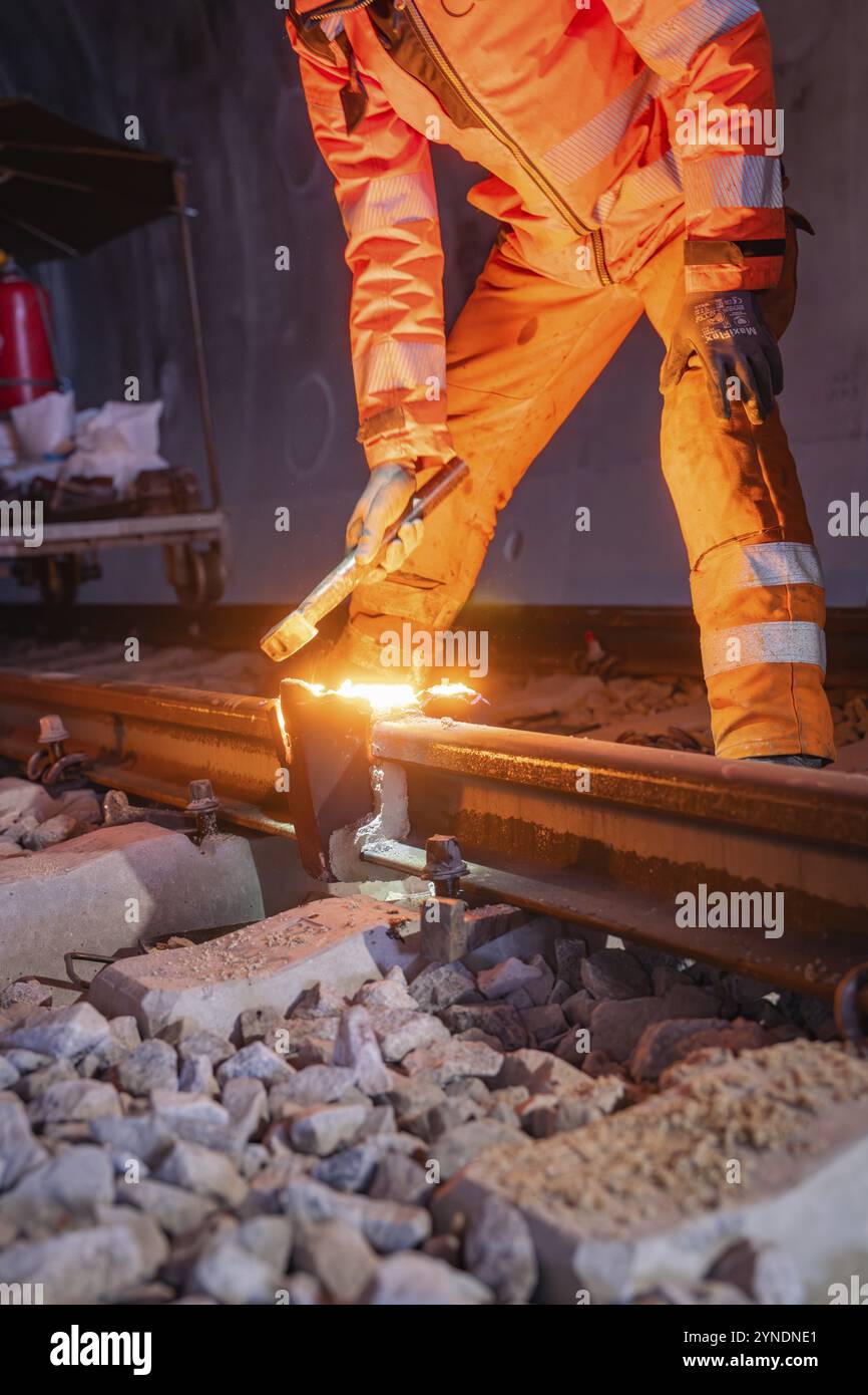 Worker welding on tracks at night, sparks spraying, concentrated ...