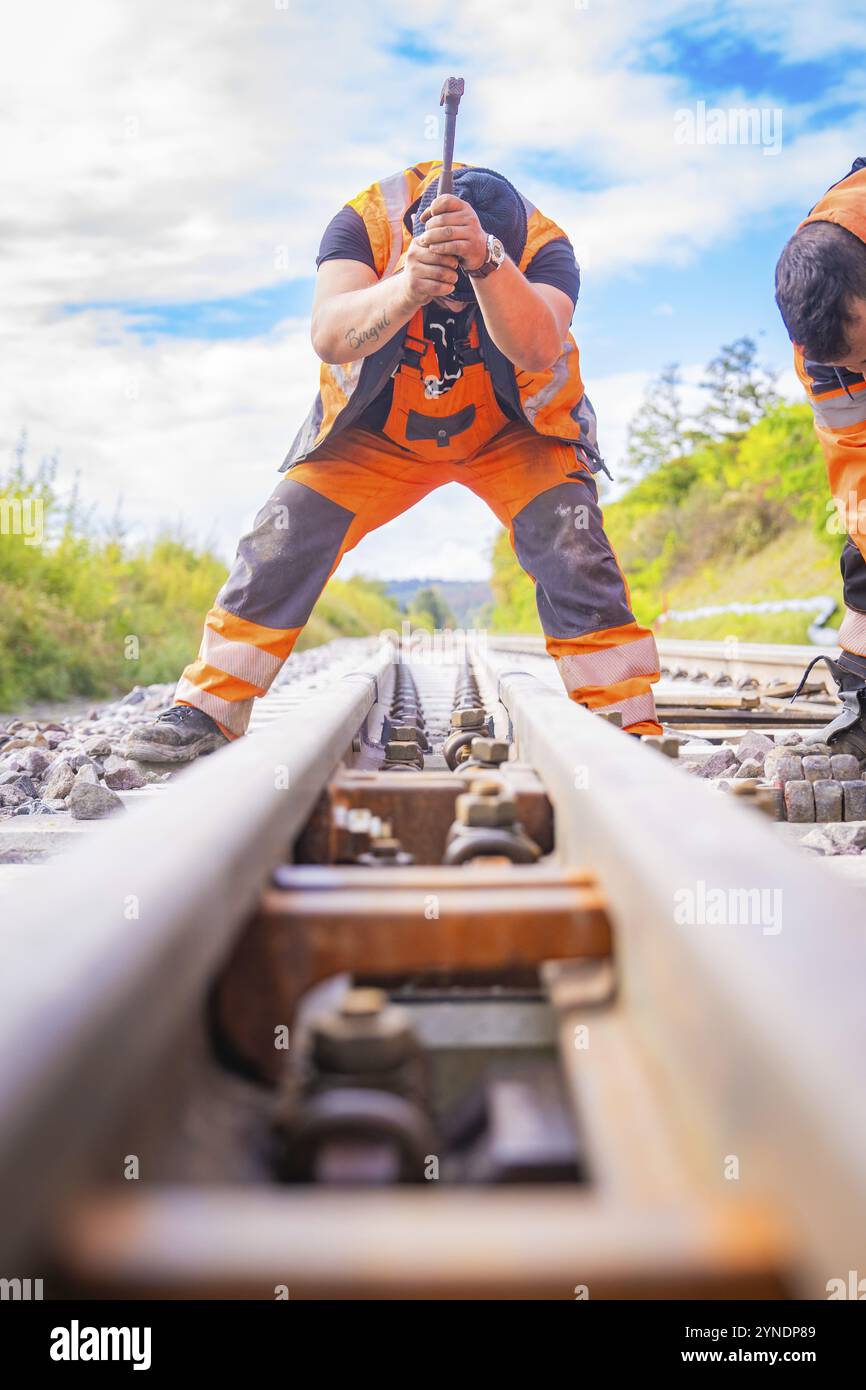 Two construction workers working on the rails, looking along the tracks ...